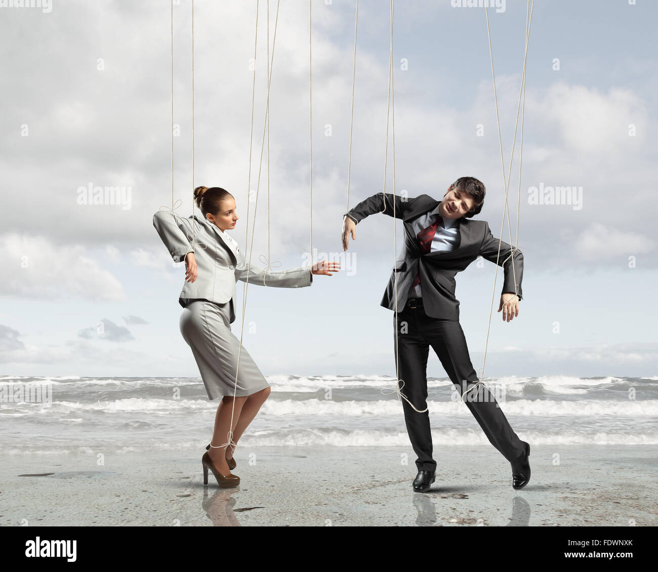 Image of businesspeople hanging on strings like marionettes against sea ...