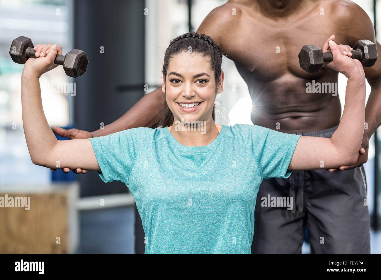 Athletic woman lifting weights helped by trainer Stock Photo - Alamy