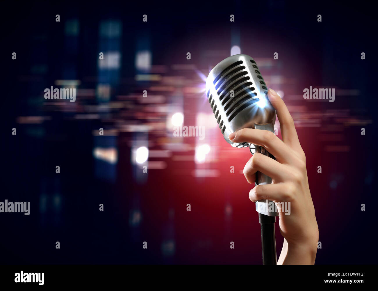Female hand holding a single retro microphone against colourful ...