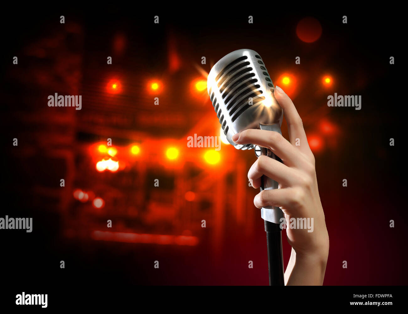 Female hand holding a single retro microphone against colourful ...