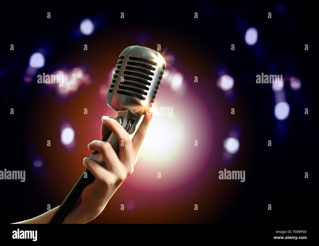 Female hand holding a single retro microphone against colourful ...
