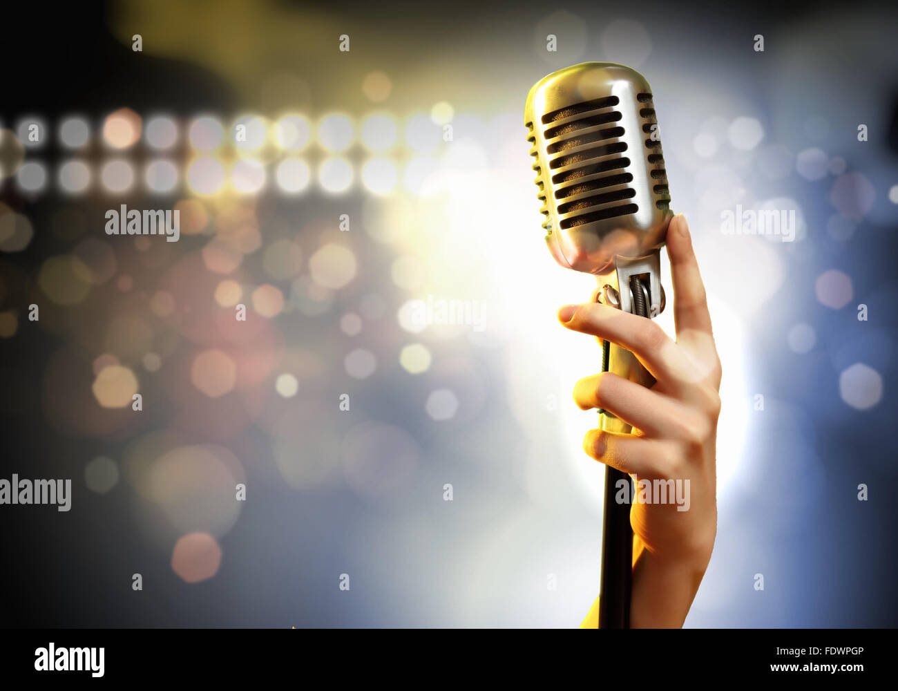 Female hand holding a single retro microphone against colourful ...