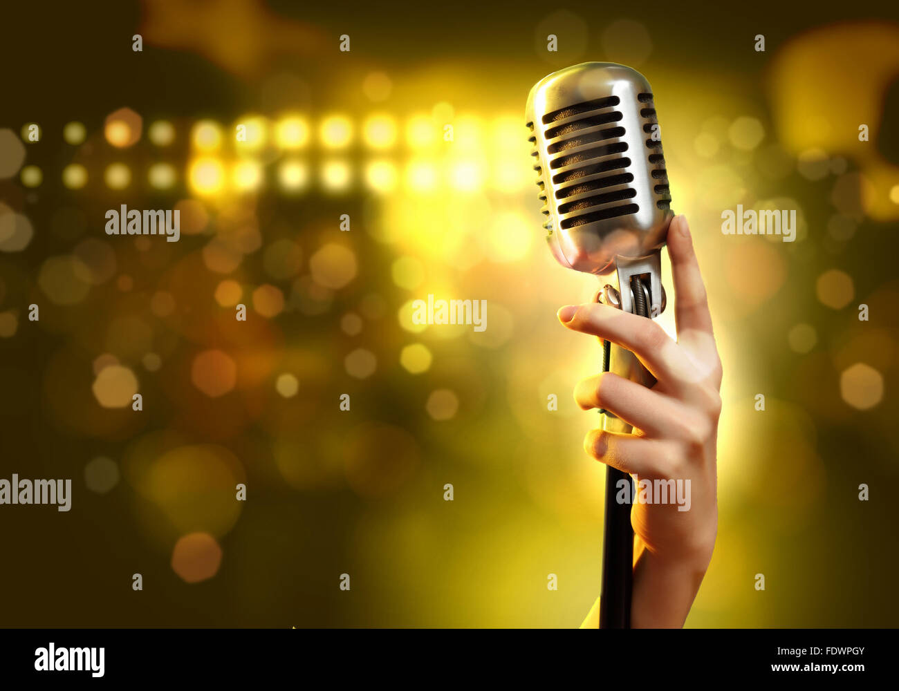 Female hand holding a single retro microphone against colourful ...