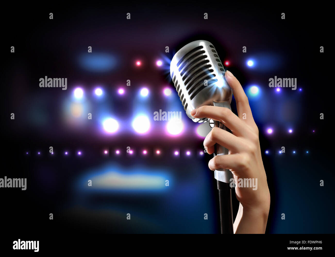 Female hand holding a single retro microphone against colourful ...
