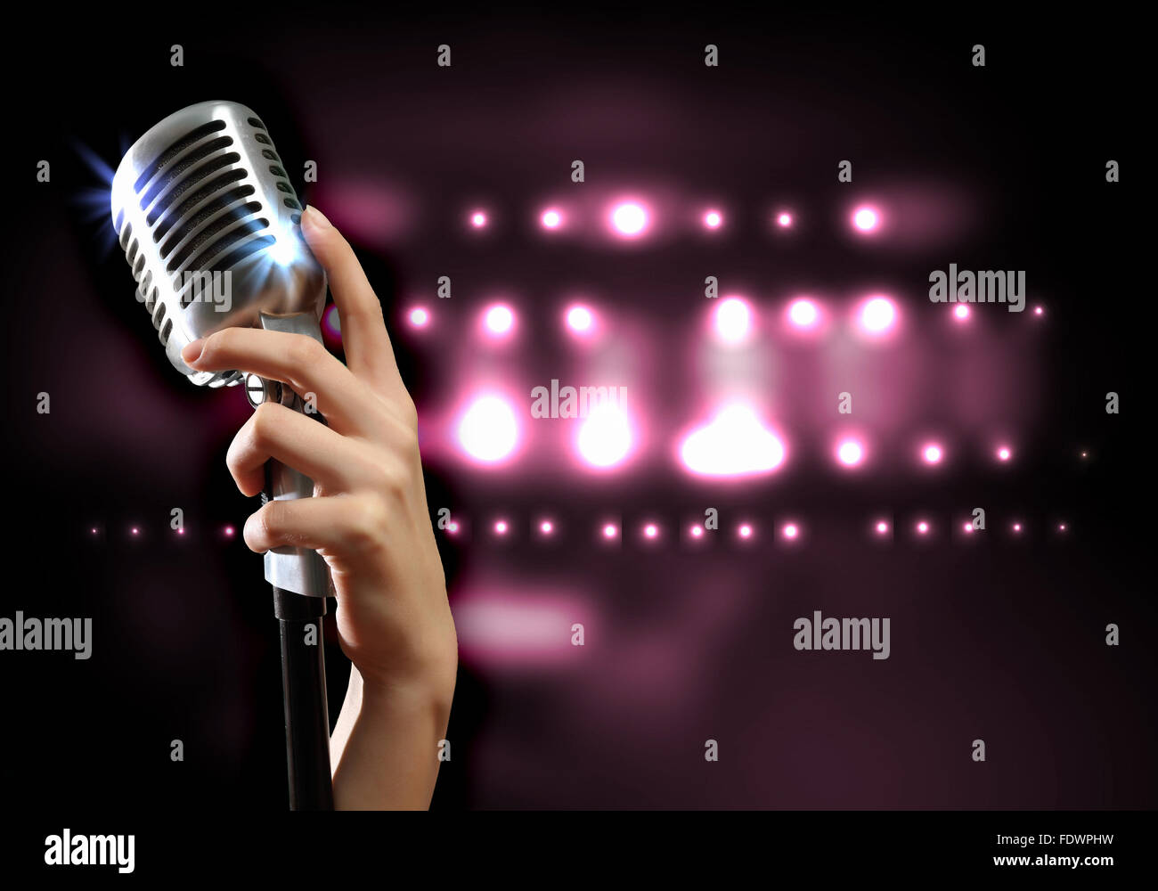 Female hand holding a single retro microphone against colourful ...