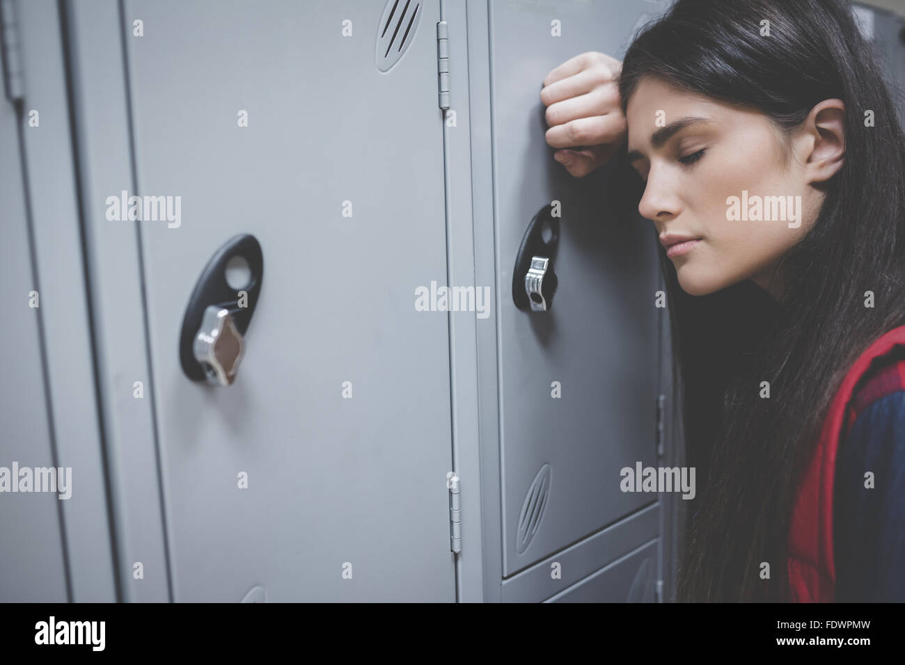 Sad student leaning on locker Stock Photo - Alamy