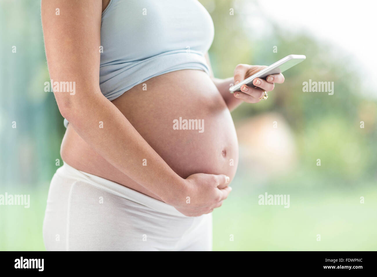 Pregnant woman touching her belly and texting Stock Photo - Alamy