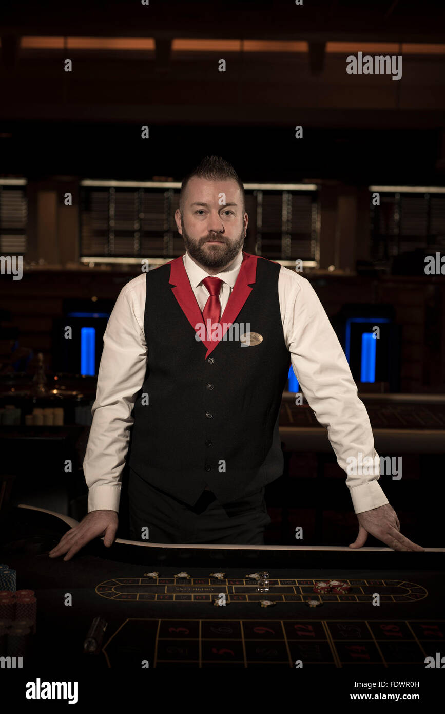 a croupier poses for the camera at a casino ready for people to start ...