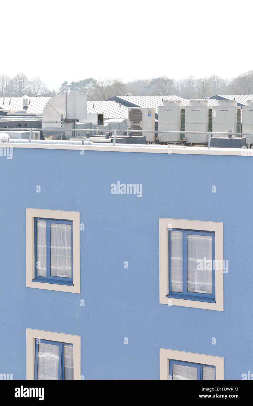 A building with a blue rendered facade and mechanical ducts on the roof ...