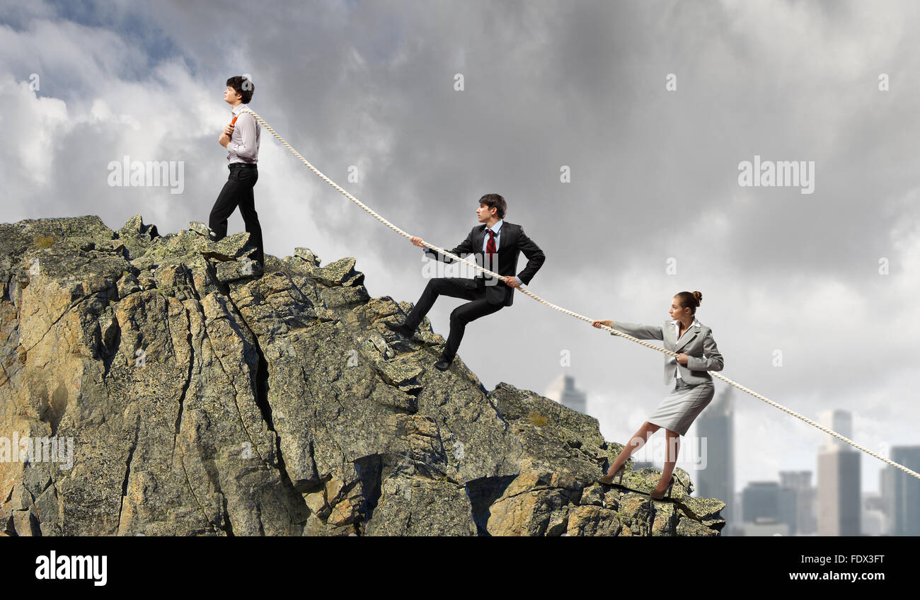 Image of three businesspeople pulling rope against city background ...