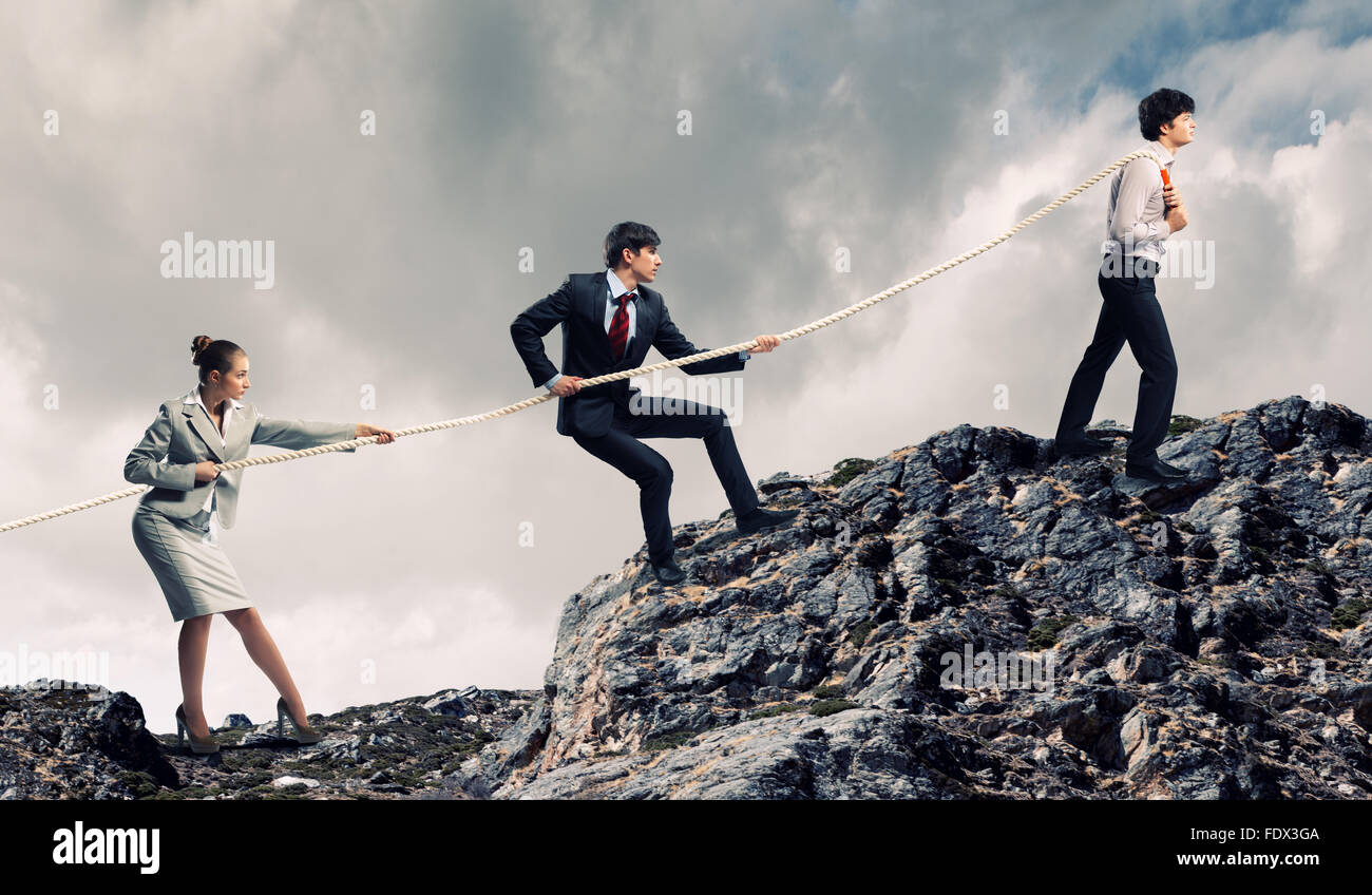 Image of three businesspeople pulling rope atop of mountain Stock Photo ...