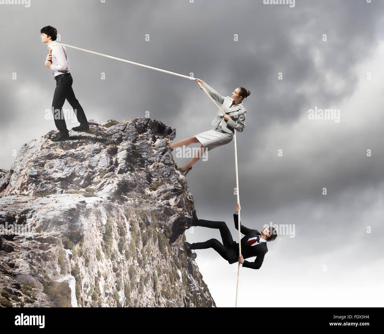 Image of three businesspeople pulling rope atop of mountain Stock Photo ...