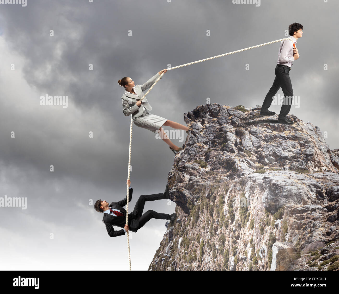 Image of three businesspeople pulling rope atop of mountain Stock Photo ...