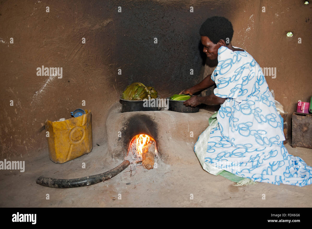 Ugandan lady preparing a meal in a pan using corn and banana leaves on ...