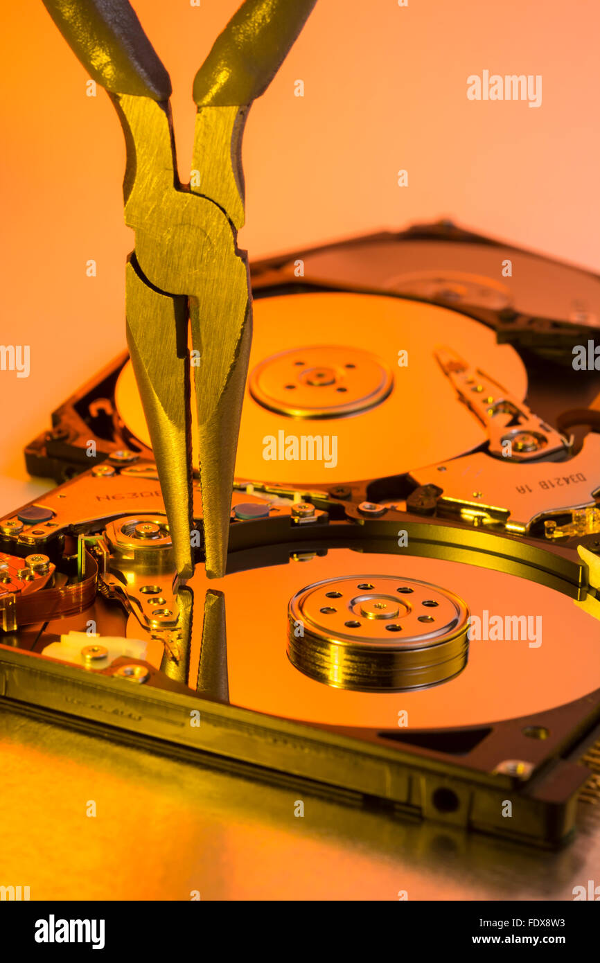 Pair of DIY pincers poised over platter of a stripped hard disk drive ...