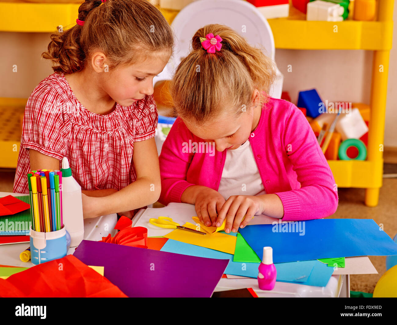 Kids holding colored paper on table in kindergarten Stock Photo - Alamy