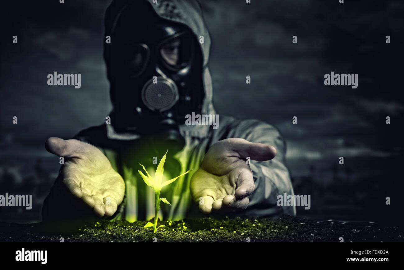 Young man in a protective suit touches to the sprout. post-nuclear ...