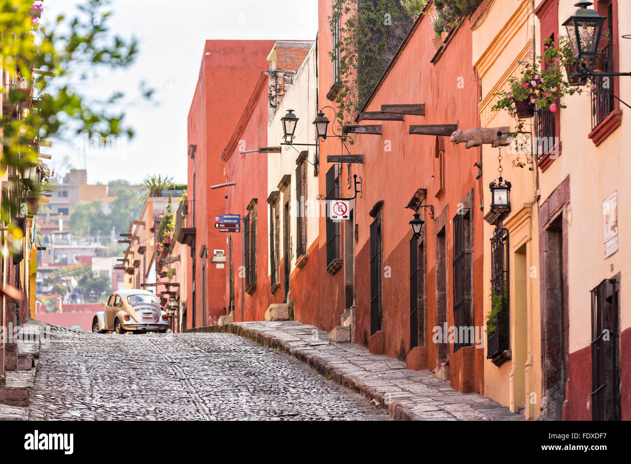 An old Volkswagen Beetle drives past Spanish colonial homes along ...
