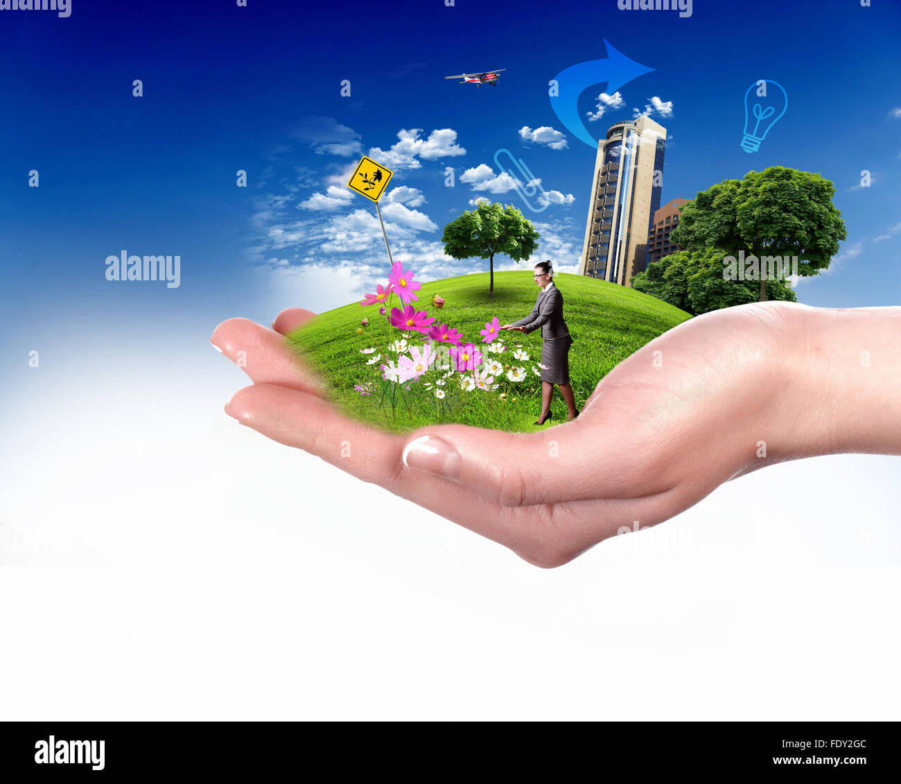 Collage with a human hand holding a green landscape Stock Photo - Alamy