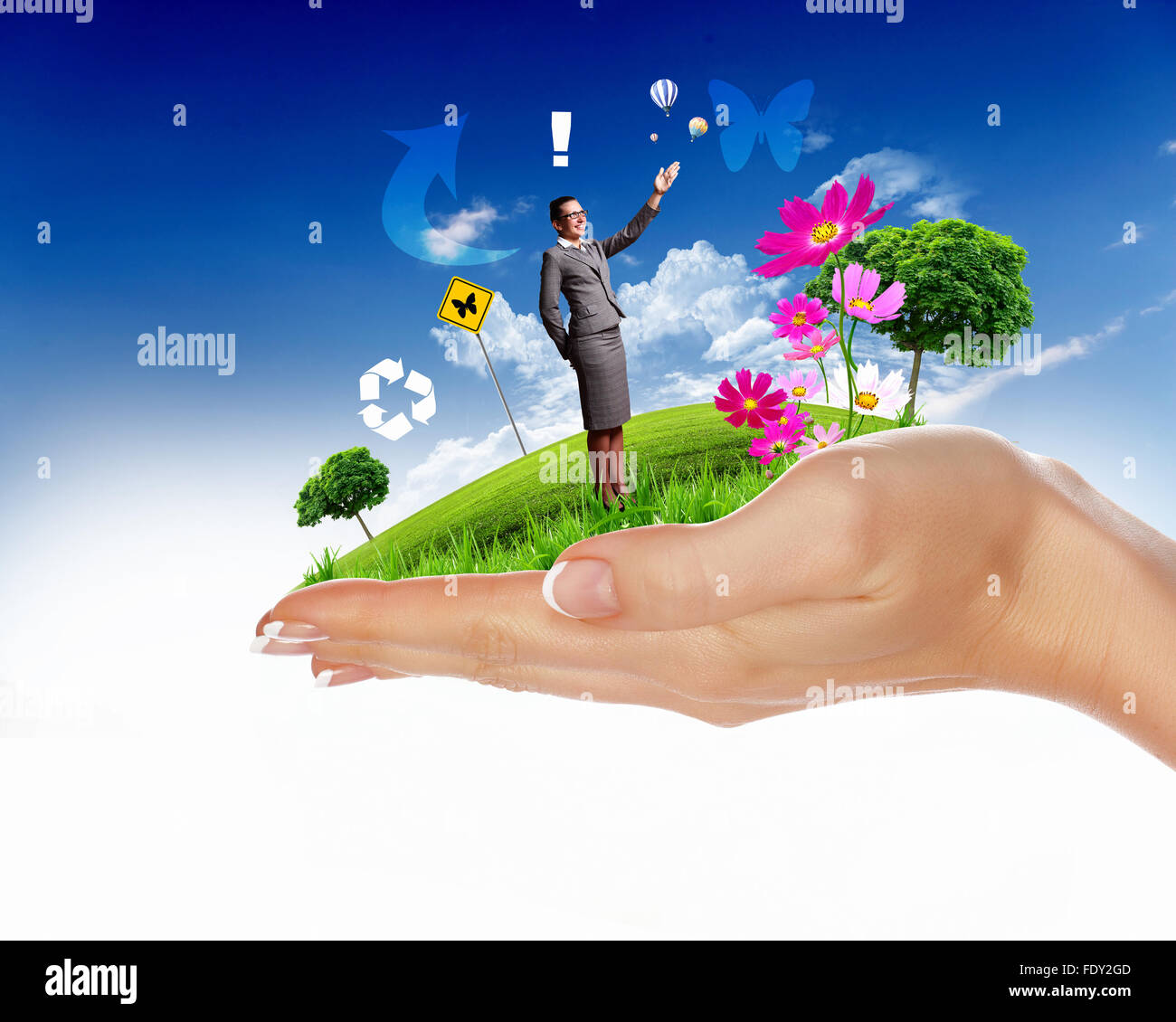 Collage with a human hand holding a green landscape Stock Photo - Alamy