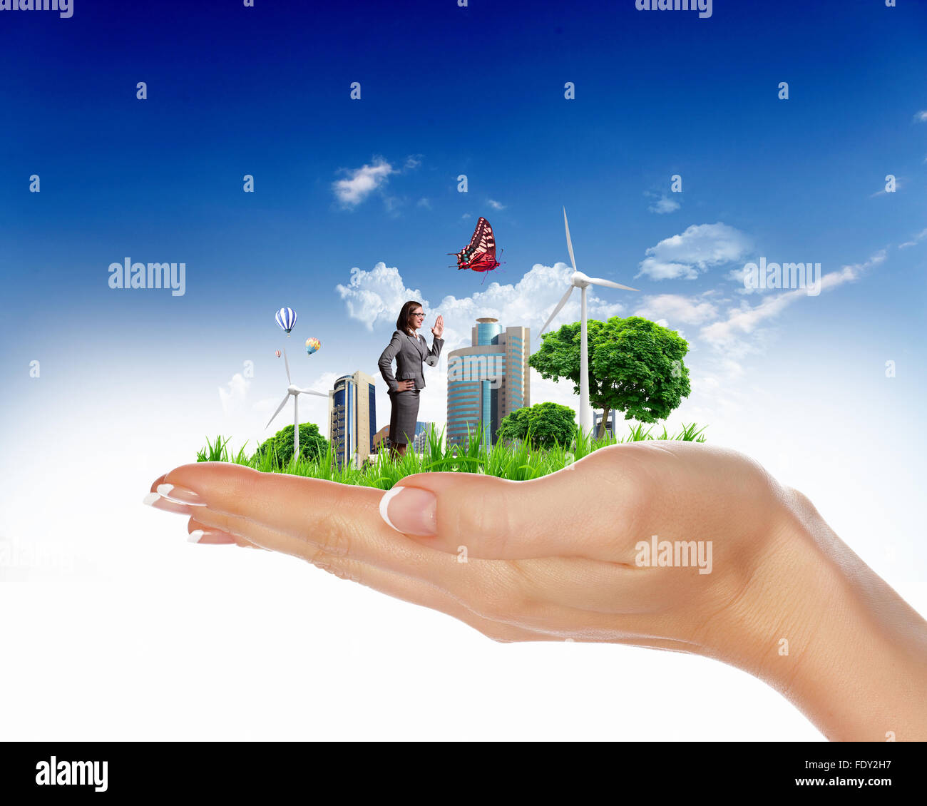 Collage with a human hand holding a green landscape Stock Photo - Alamy