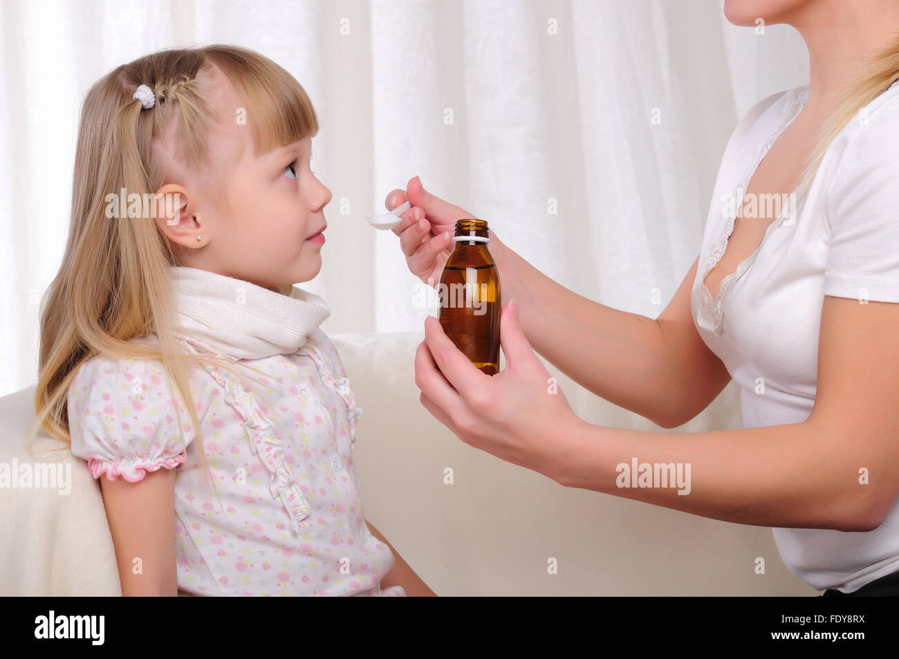 Little girl drinking cough syrup with a small spoon from the hands of ...