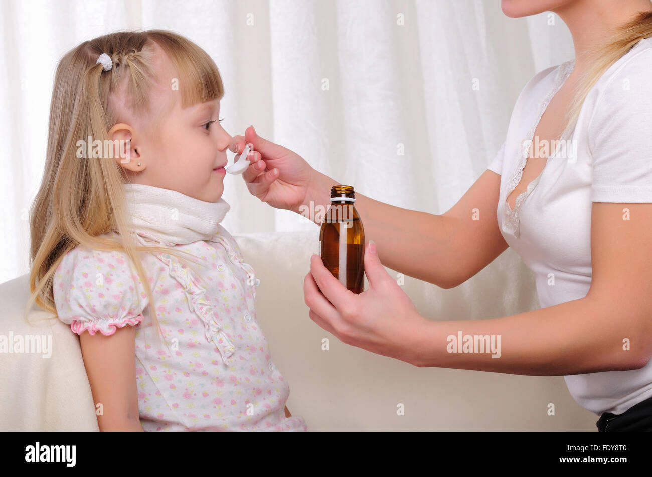 Little girl drinking cough syrup with a small spoon from the hands of ...