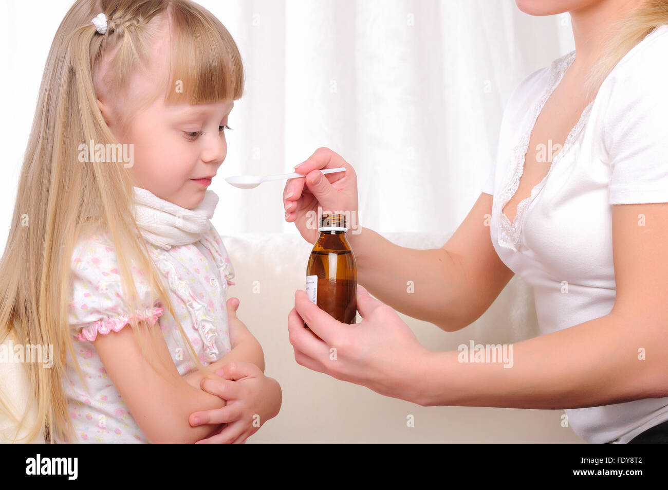 Little girl drinking cough syrup with a small spoon from the hands of ...