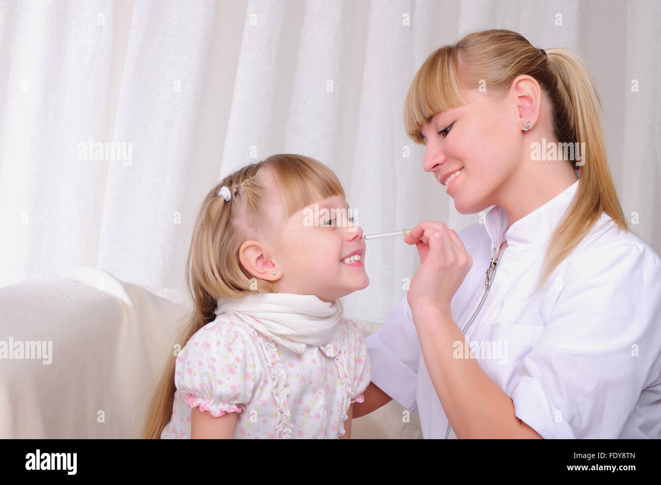 Young woman doctor is dripping a drop in the spout of his little ...