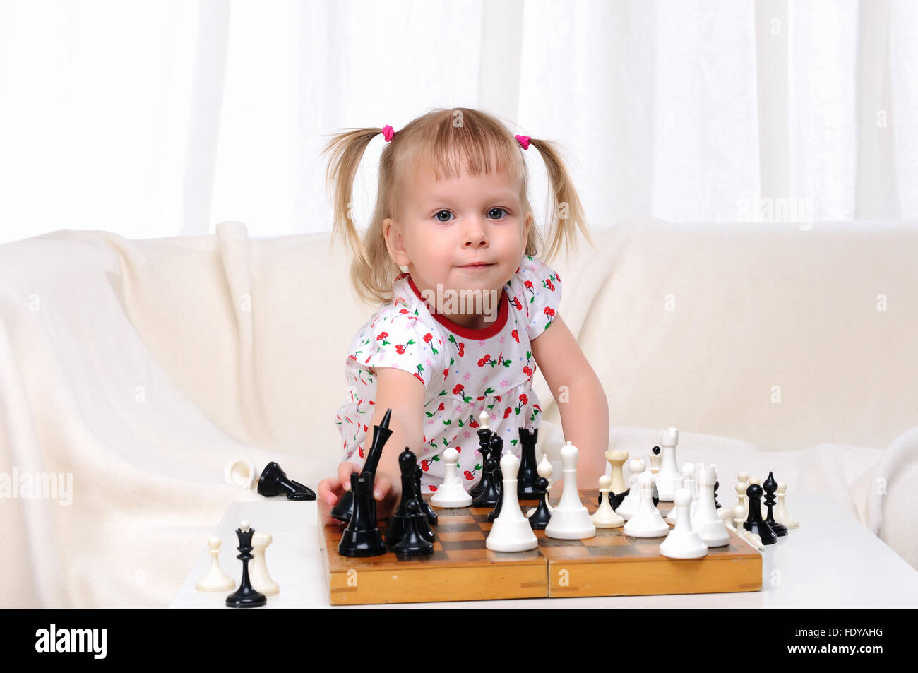 Little girl playing chess at a table Stock Photo - Alamy