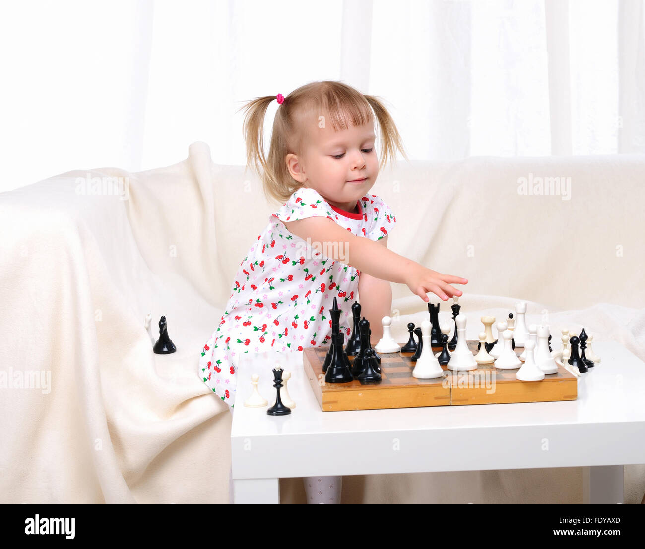Little girl playing chess at a table Stock Photo - Alamy