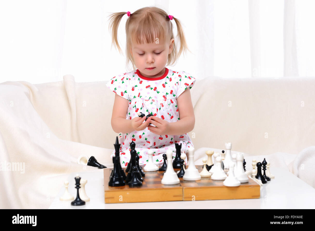 Little girl playing chess at a table Stock Photo - Alamy