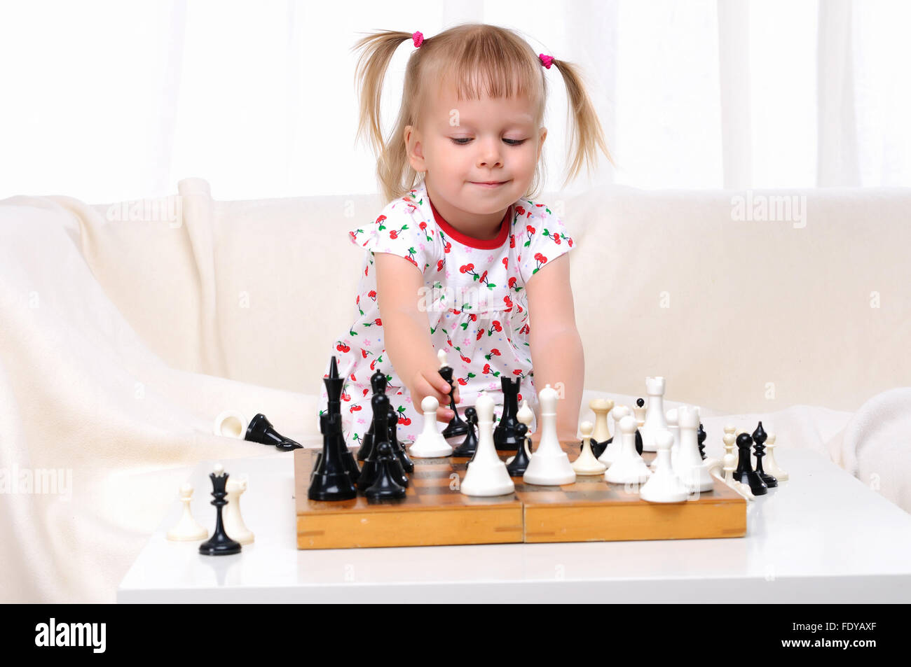 Little girl playing chess at a table Stock Photo - Alamy