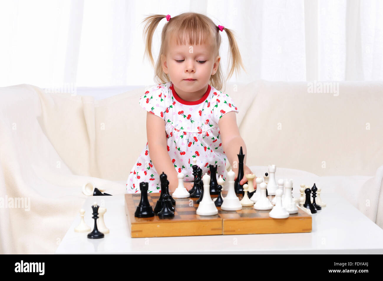 Little girl playing chess at a table Stock Photo - Alamy