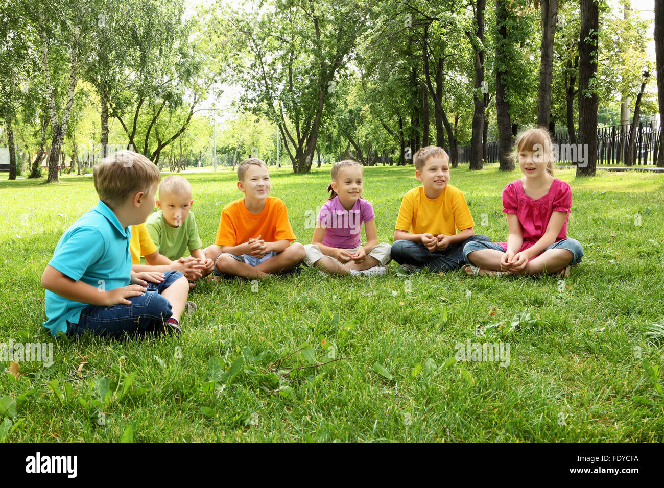 Group of children sitting together on teh grass in the park Stock Photo ...