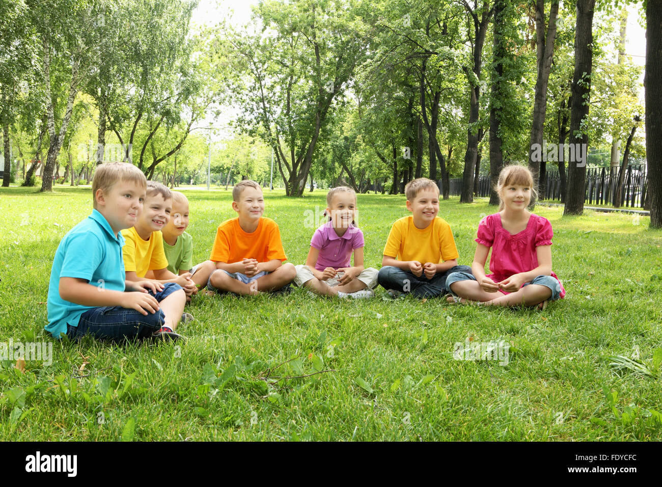Group of children sitting together on teh grass in the park Stock Photo ...