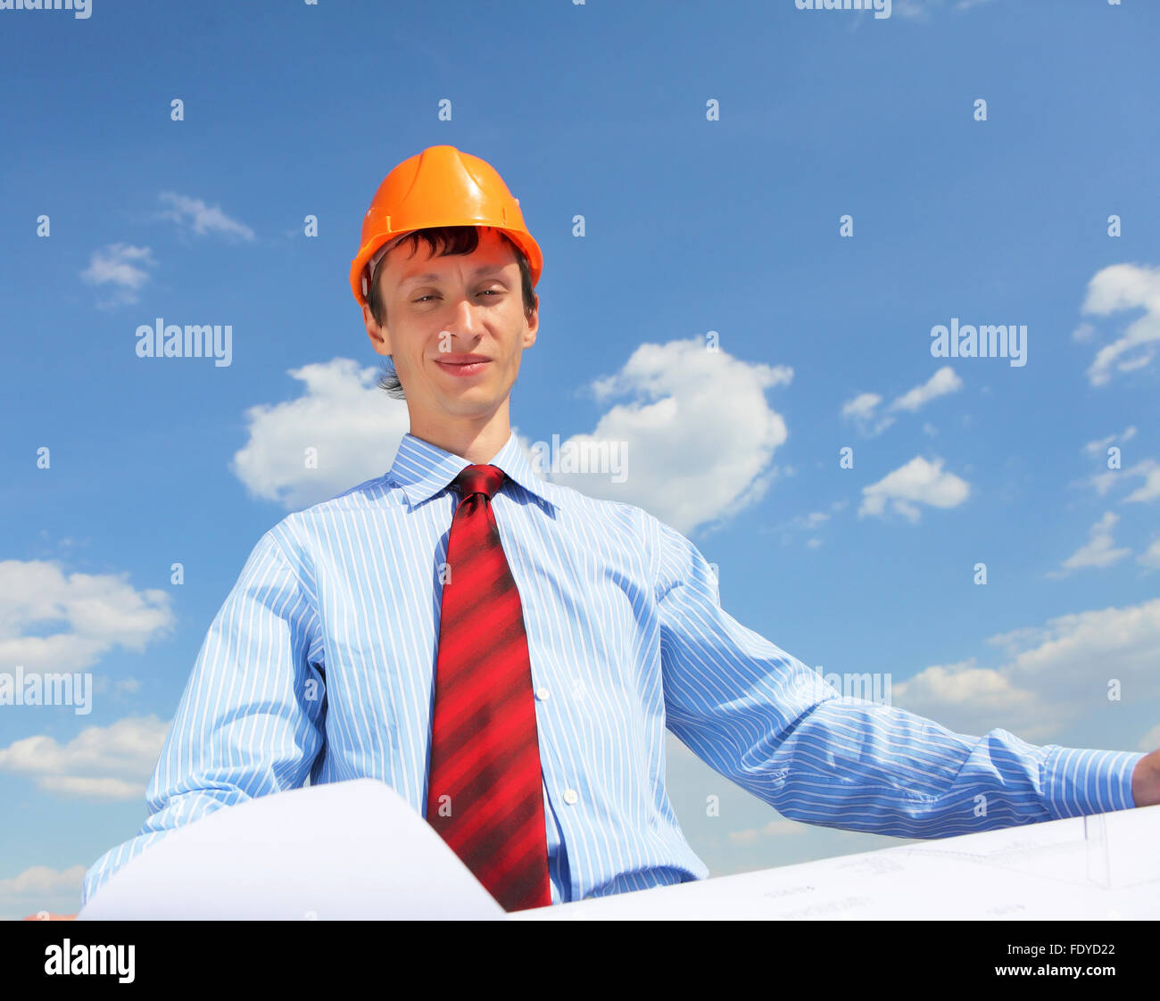 young engineer in blue shirt and yellow helmet against blue sky Stock ...