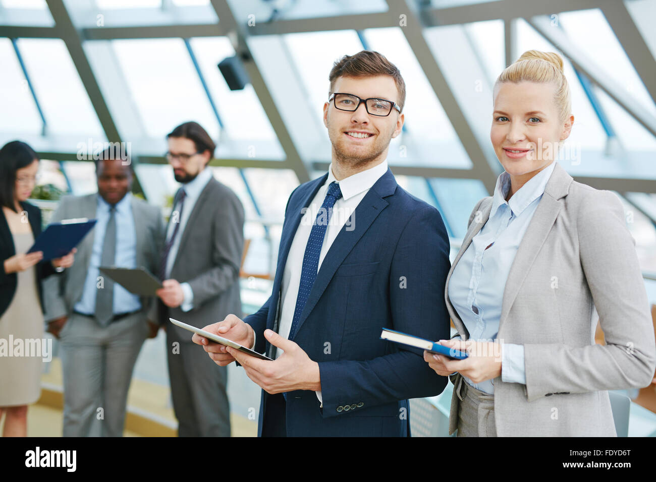Young colleagues looking at camera in working environment Stock Photo ...