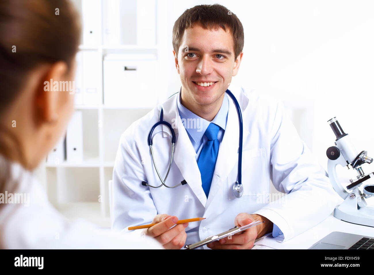 Young confident and friendly doctor in medical office Stock Photo - Alamy