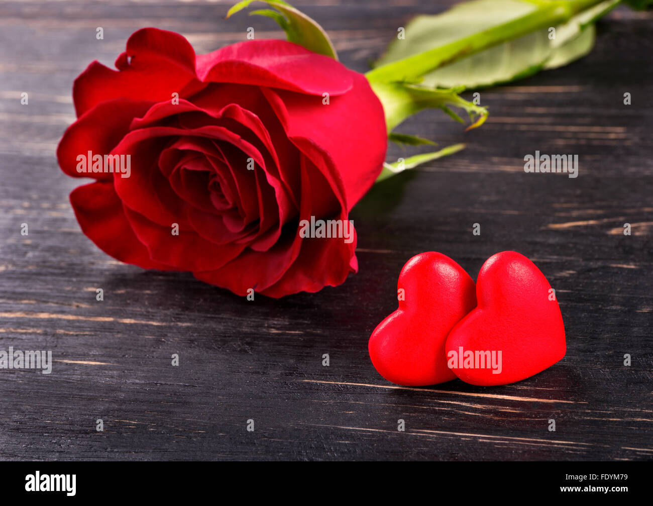 Red rose with two hearts on a dark wooden background Stock Photo - Alamy