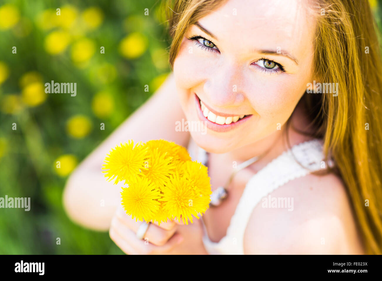 Portrait of beautiful girl with bouquet of yellow dandelions outdoor in ...