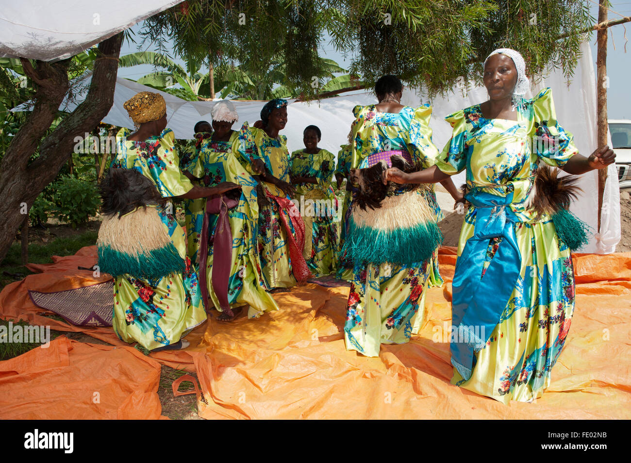 Ugandan women and children performing a traditional welcome dance for ...