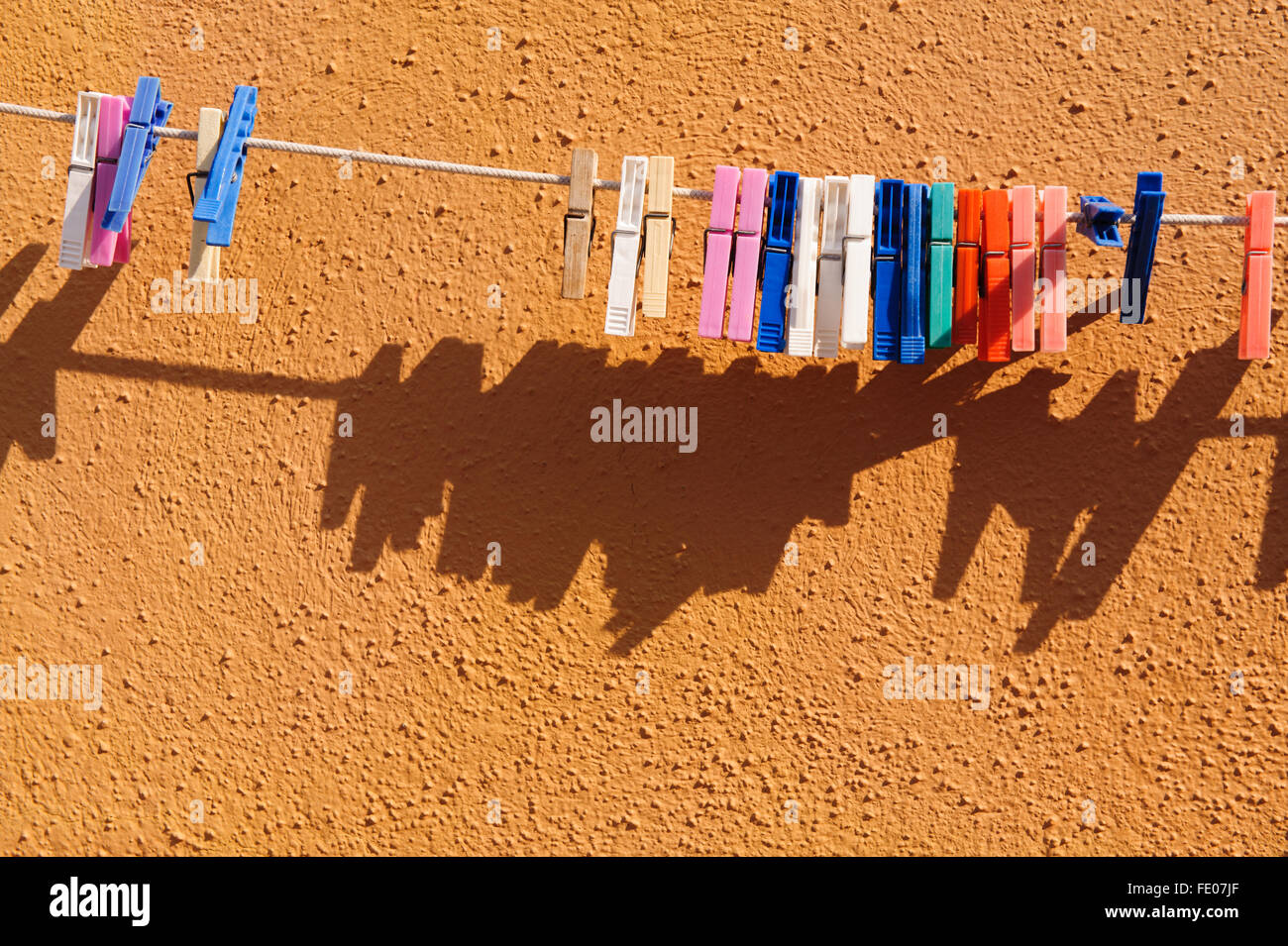 Pegs and shadows against orange painted house Stock Photo - Alamy