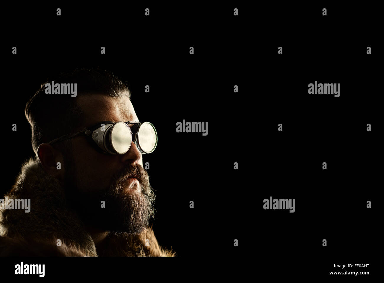 Studio shot of a young man with beard and a black goggles on black ...