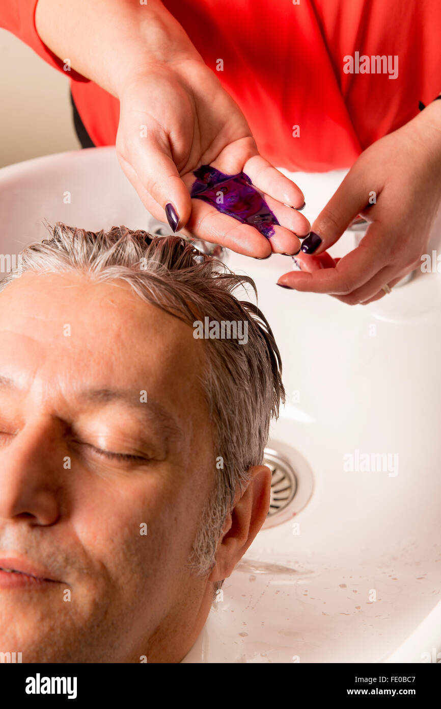 Close up of face of man is getting a hairwash by a hairdresser, with ...