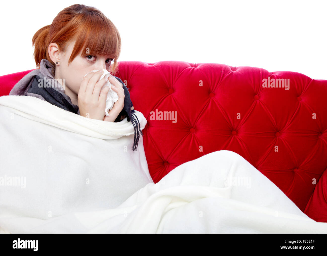 young beautiful red haired girl on red sofa is sick in front of white ...