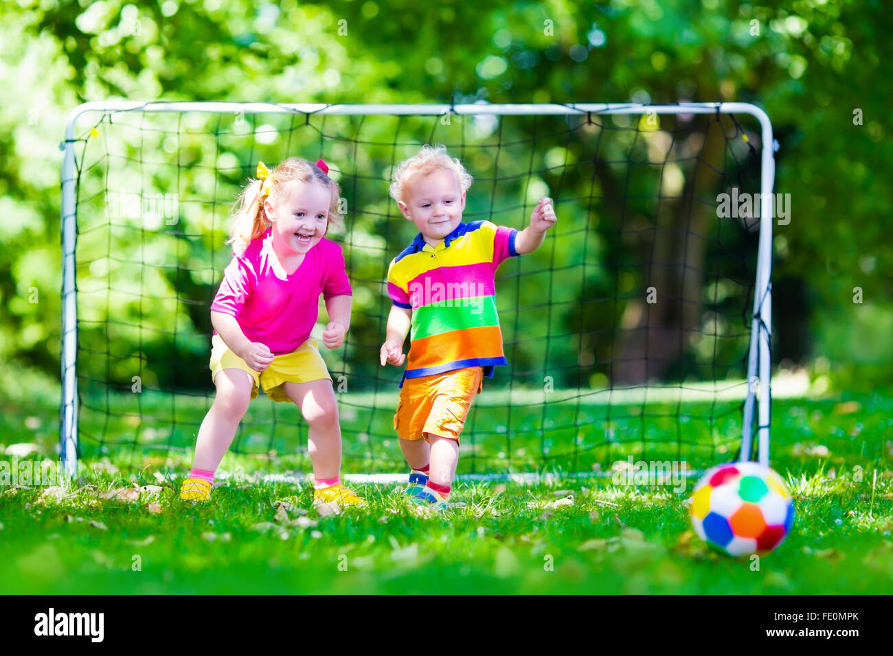 Two happy children playing European football outdoors in school yard ...