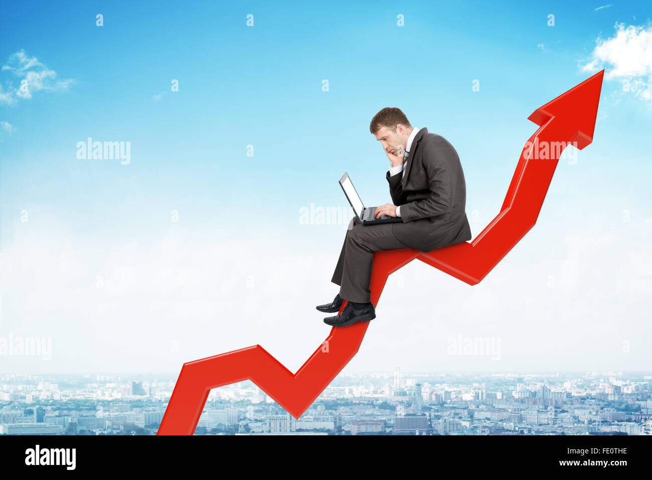 Sad businessman sitting on big red arrow Stock Photo - Alamy