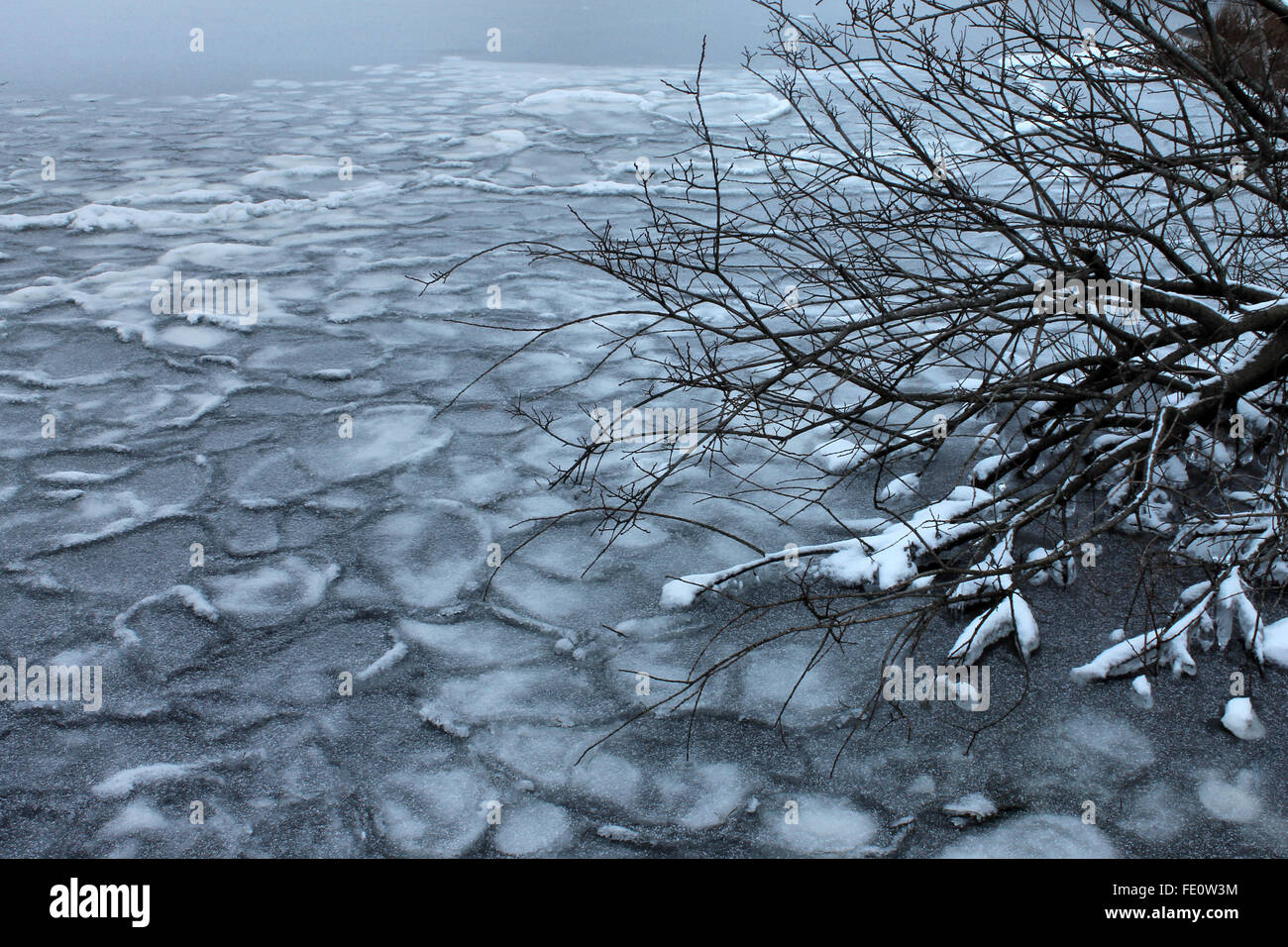 Patterns of ice on surface of frozen Ogwen lake with dusting of snow ...