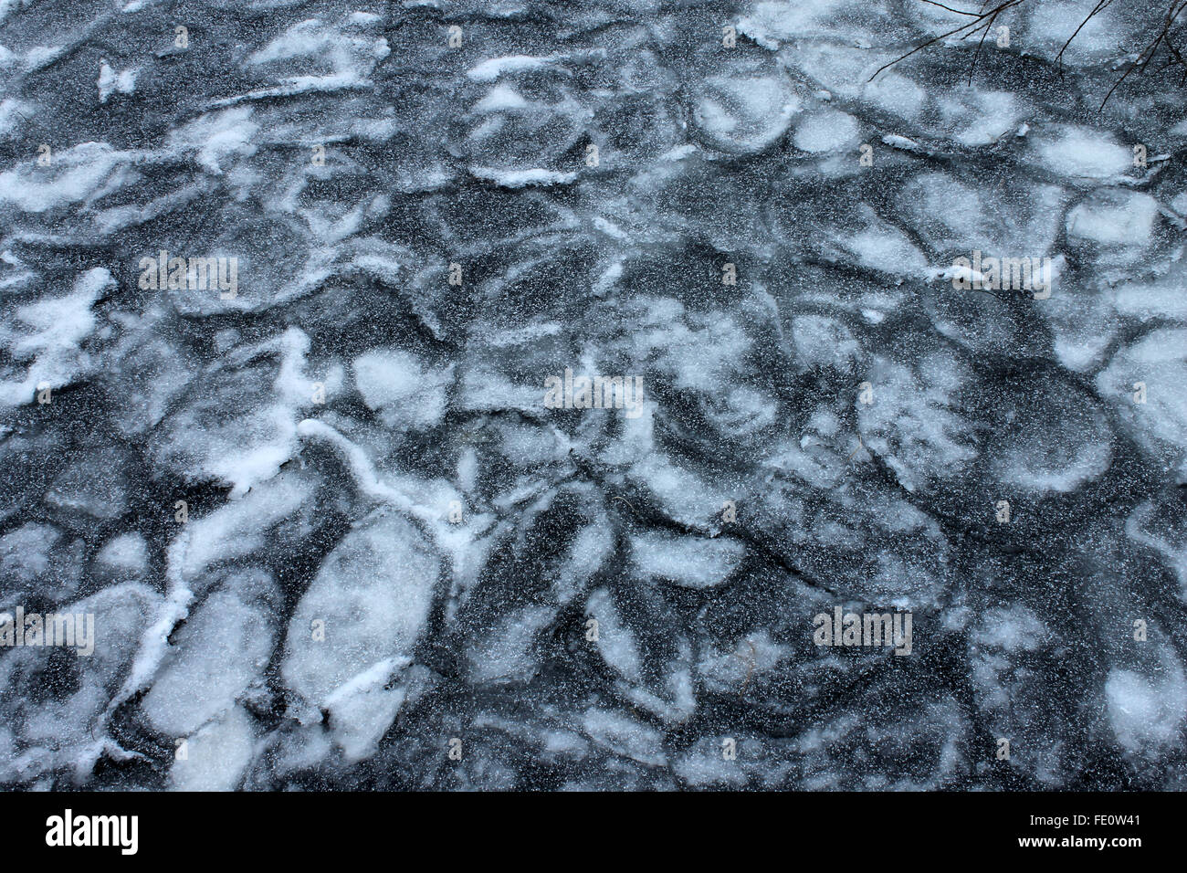 Patterns of ice on surface of frozen Ogwen lake with dusting of snow ...
